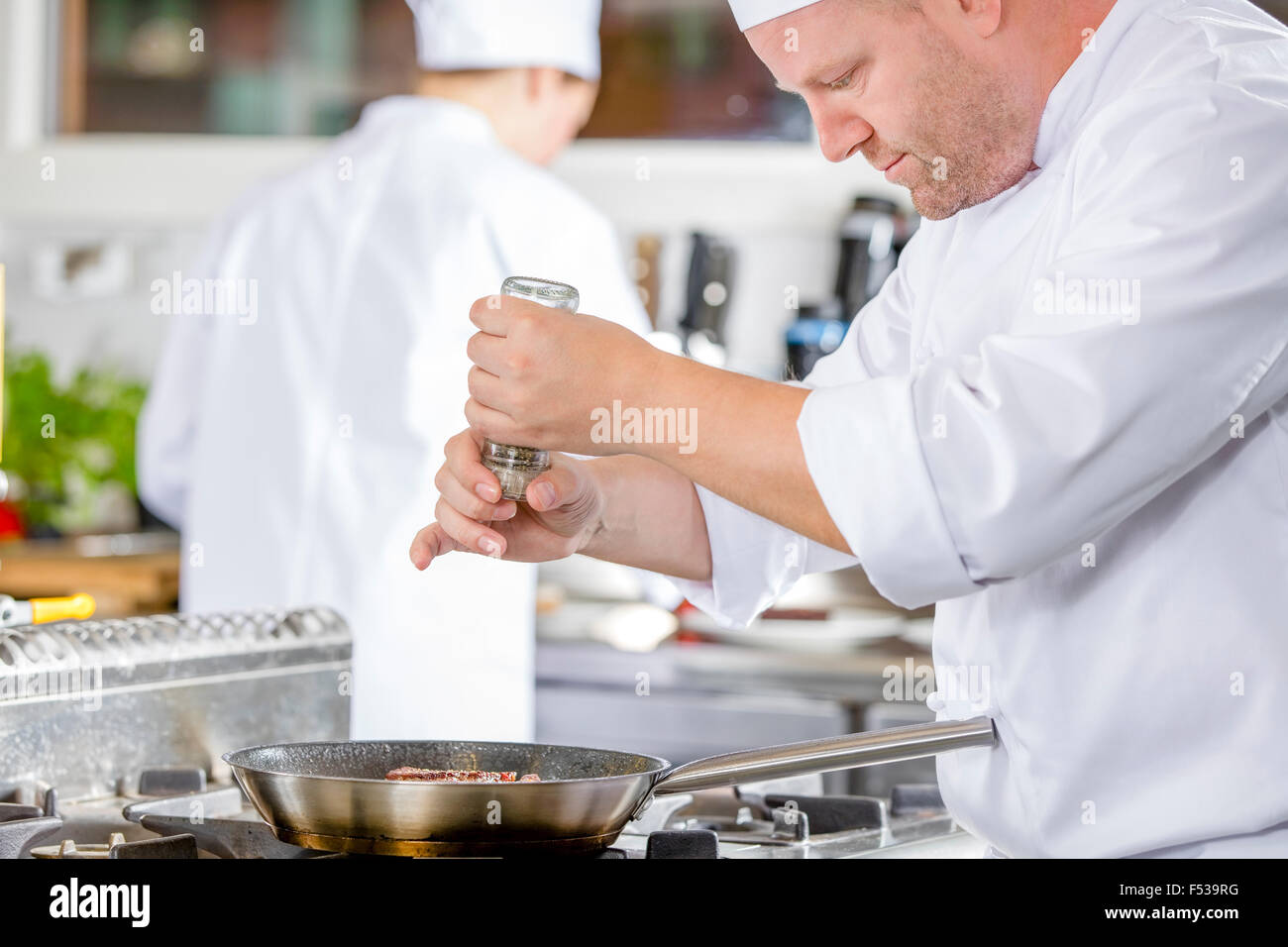Chef adding pepper on steak in the kitchen Stock Photo - Alamy