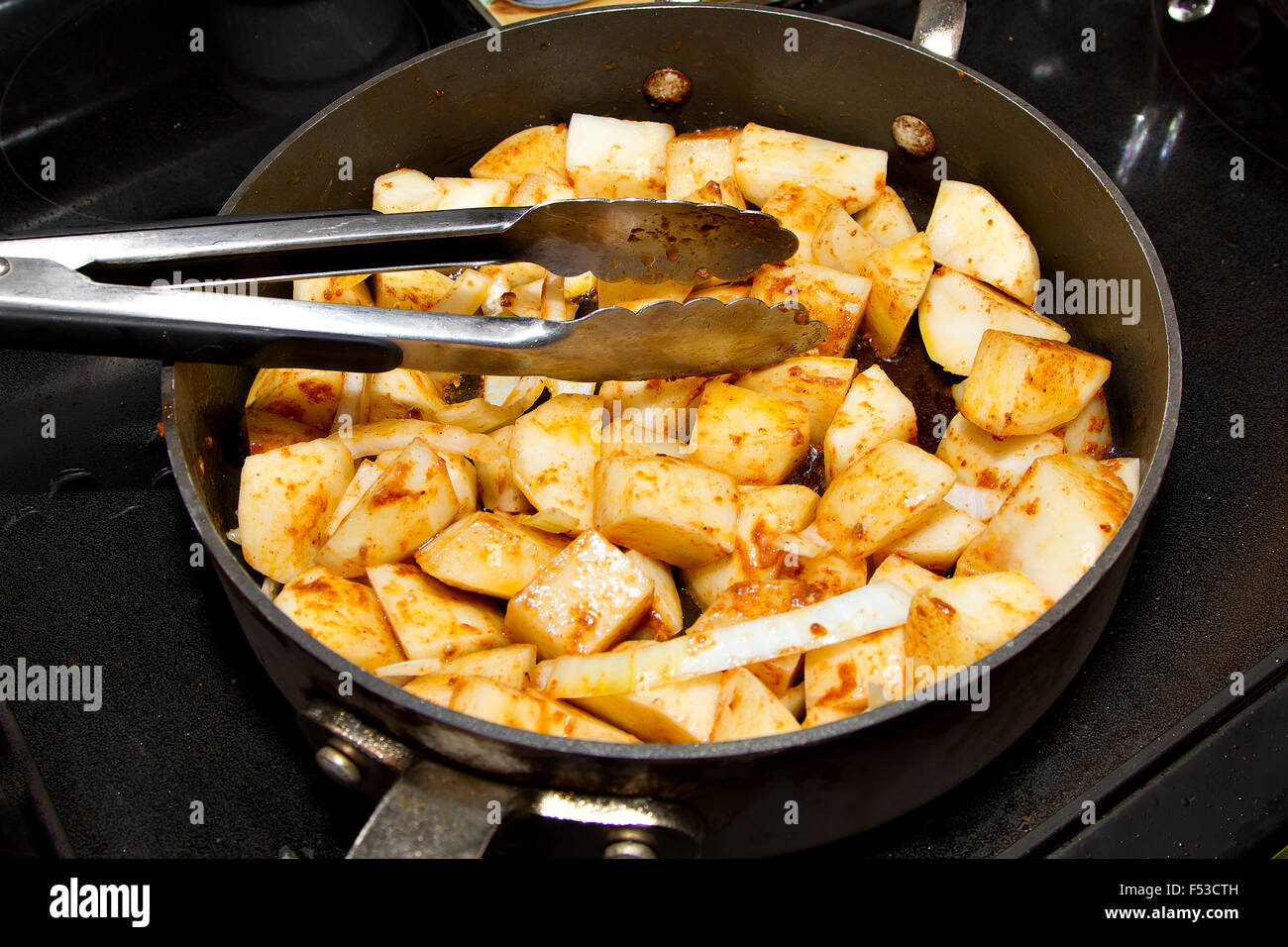 Spicy potato skillet dinner. Hand shown turning potatoes Stock Photo ...