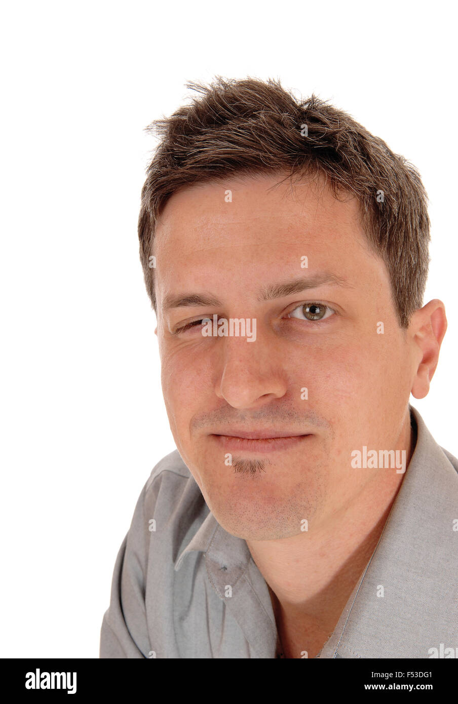 A closeup head shoot of a handsome young man, closing one eye, isolated ...