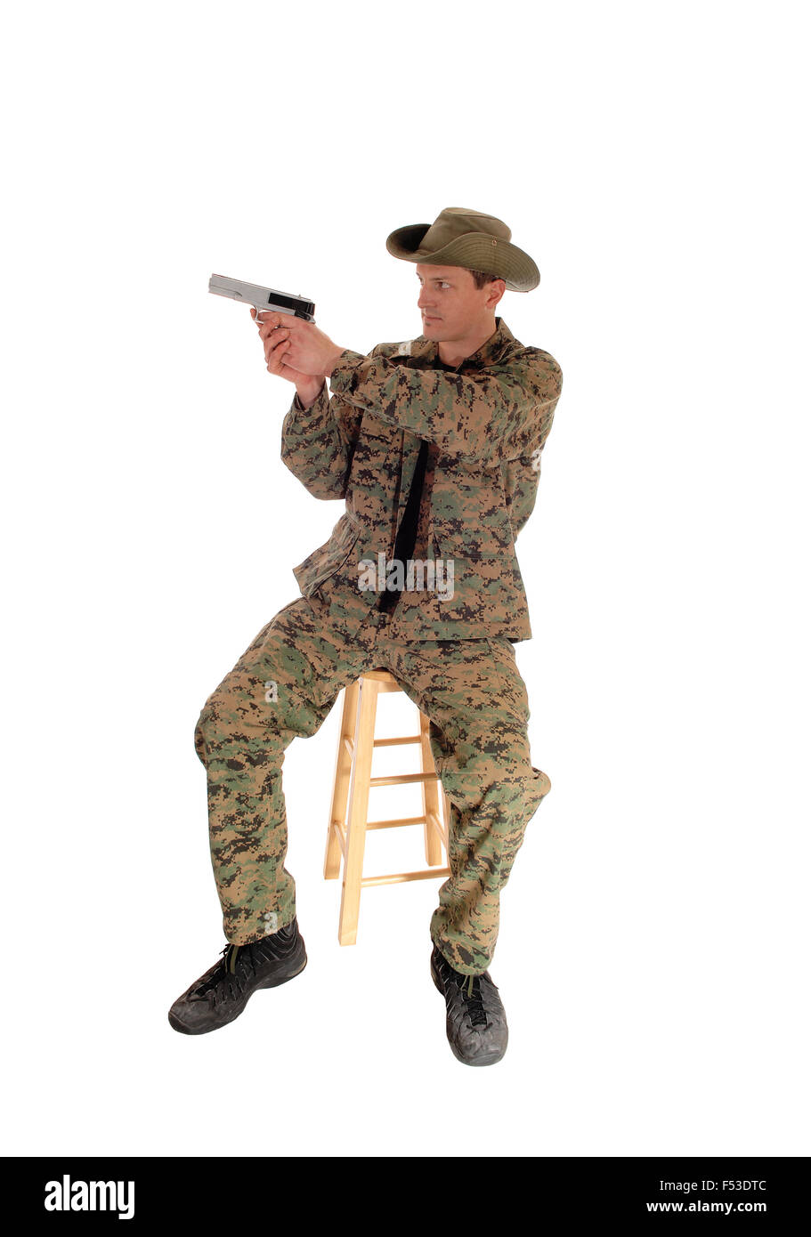 A soldier in a camouflage uniform sitting on a chair, pointing his ...