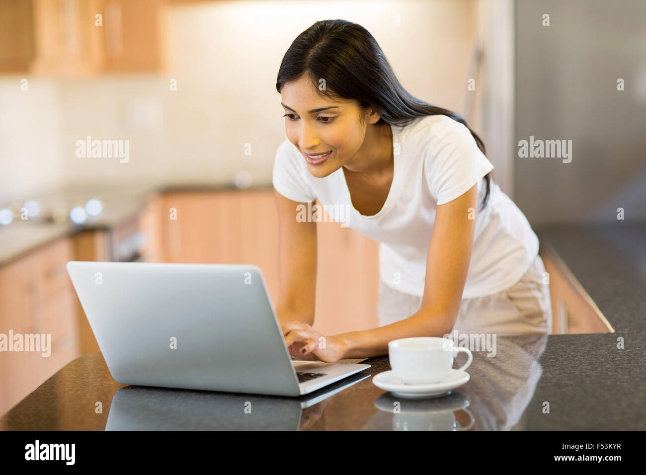 happy young Indian woman using laptop computer in the kitchen Stock ...