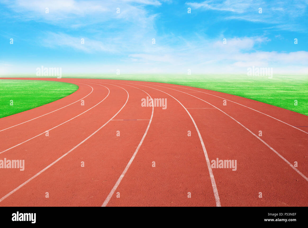 empty outdoor running track with green grass and blue sky Stock Photo ...