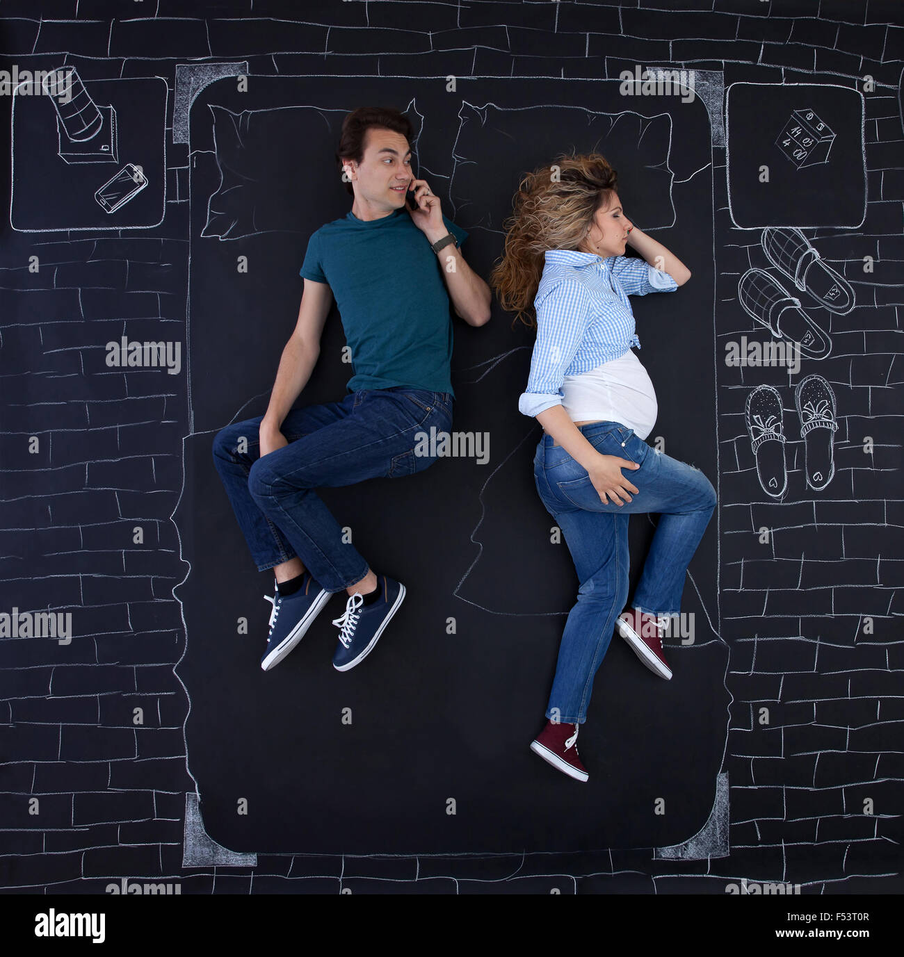 Young couple doing activities in bed. The man is talking on the phone ...