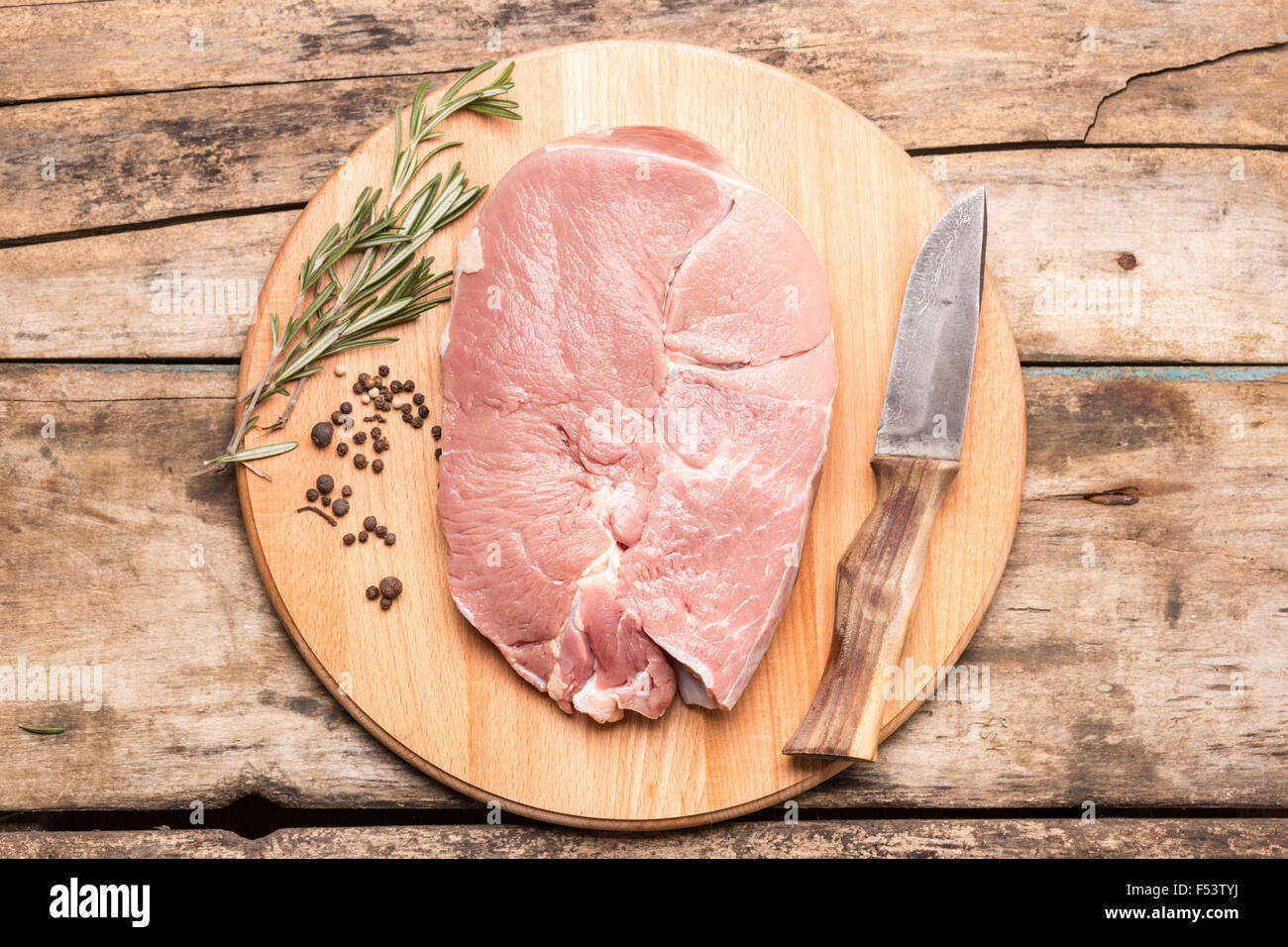 Huge chunk of meat with herbs and peppers on cutting board. Top view ...