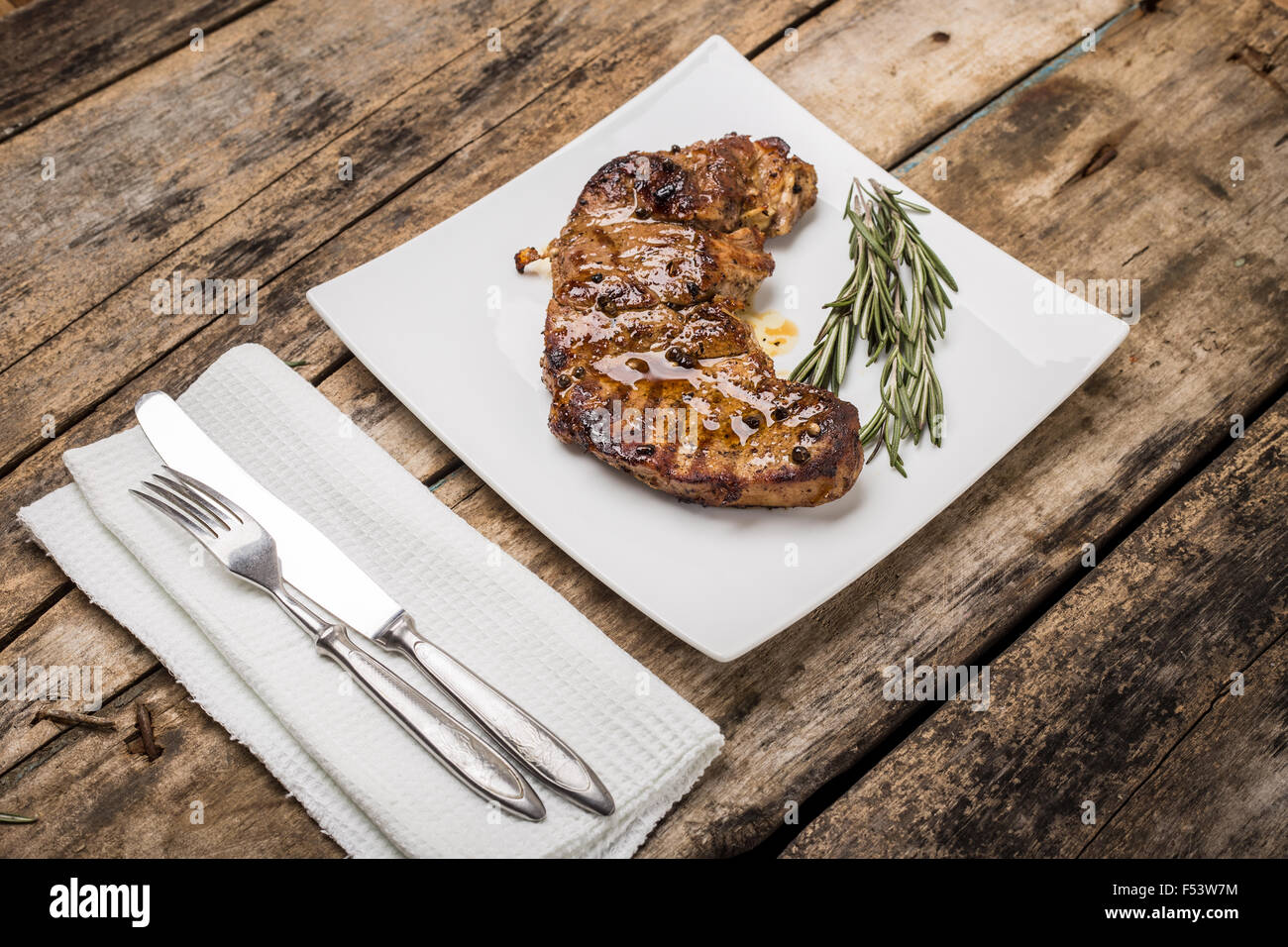 Grilled beefsteak decorated with rosemary bunch on white plate ...