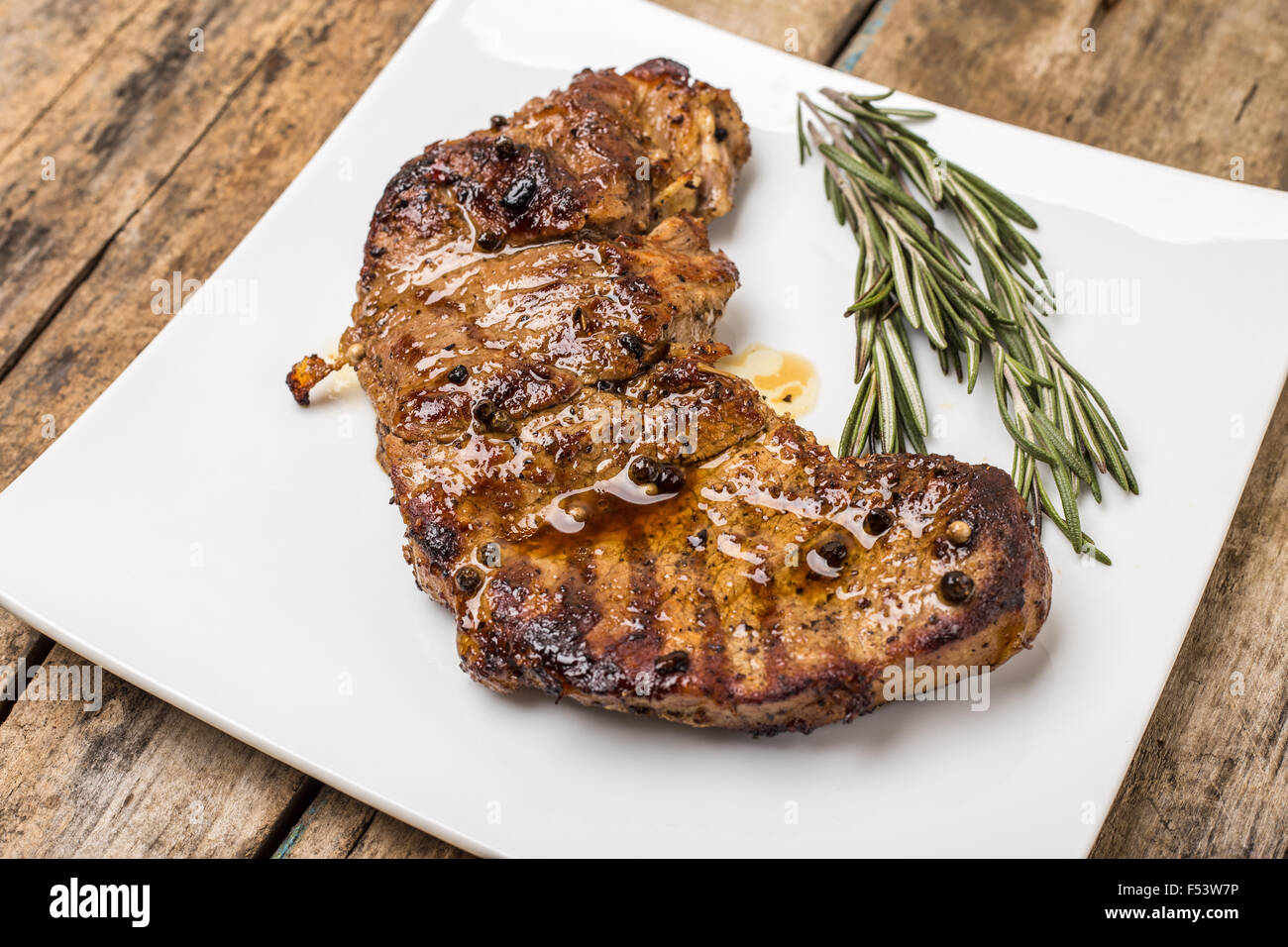 Grilled beefsteak decorated with rosemary bunch on white plate ...