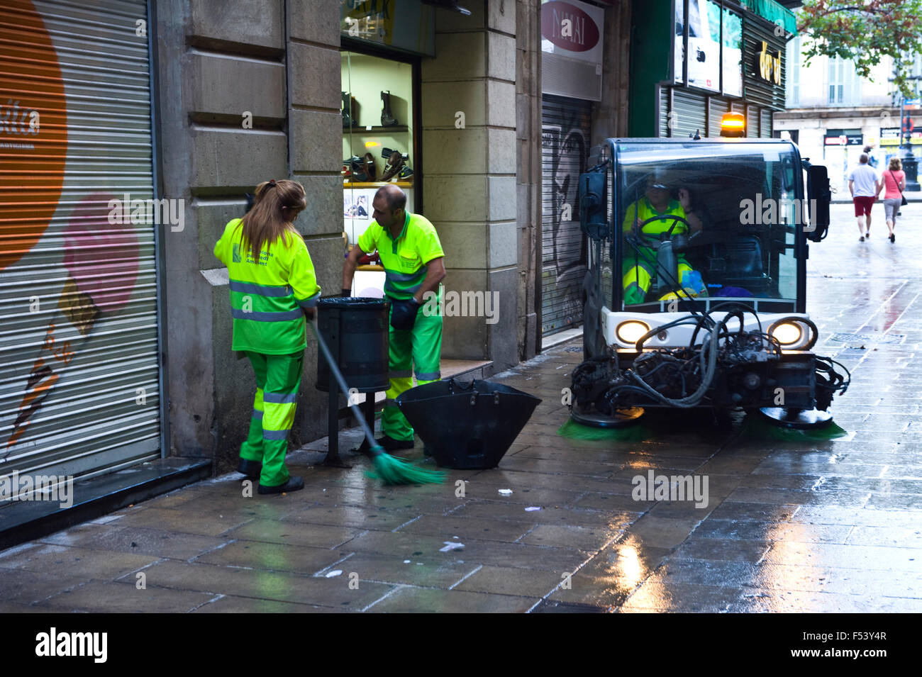 Street cleaners emptying litter bin & sweeping street in Barcelona ...