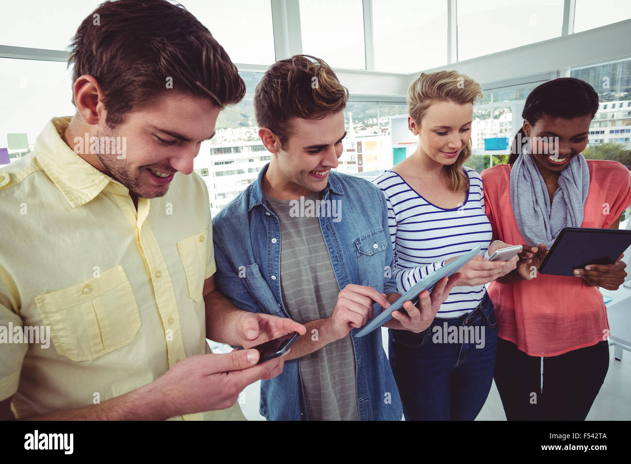 Smiling creative team standing in a line using technology Stock Photo ...