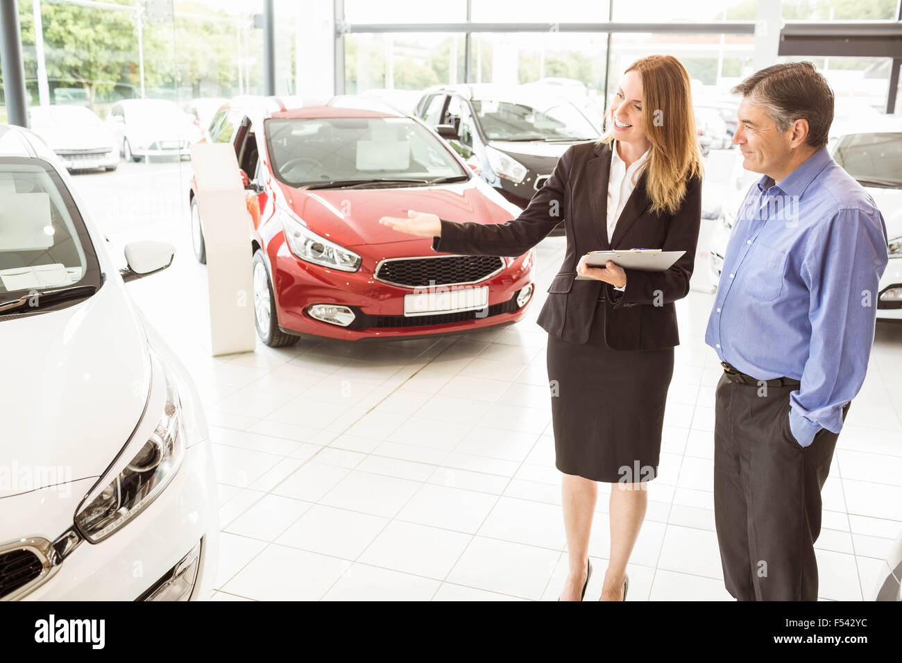 Smiling businesswoman showing car to customer Stock Photo - Alamy
