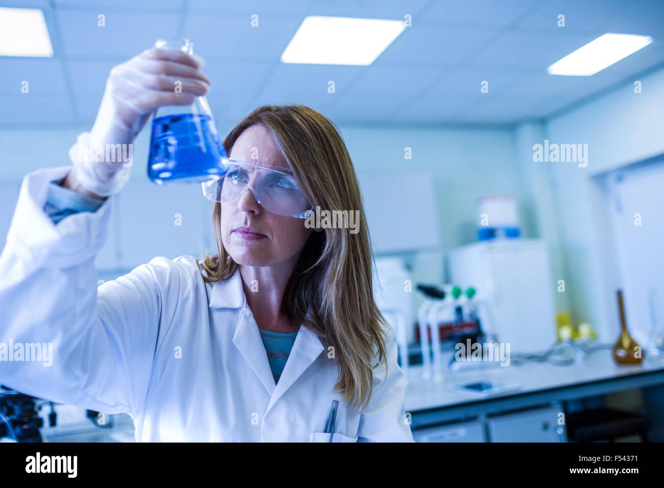 Scientist holding up beaker of chemical Stock Photo - Alamy