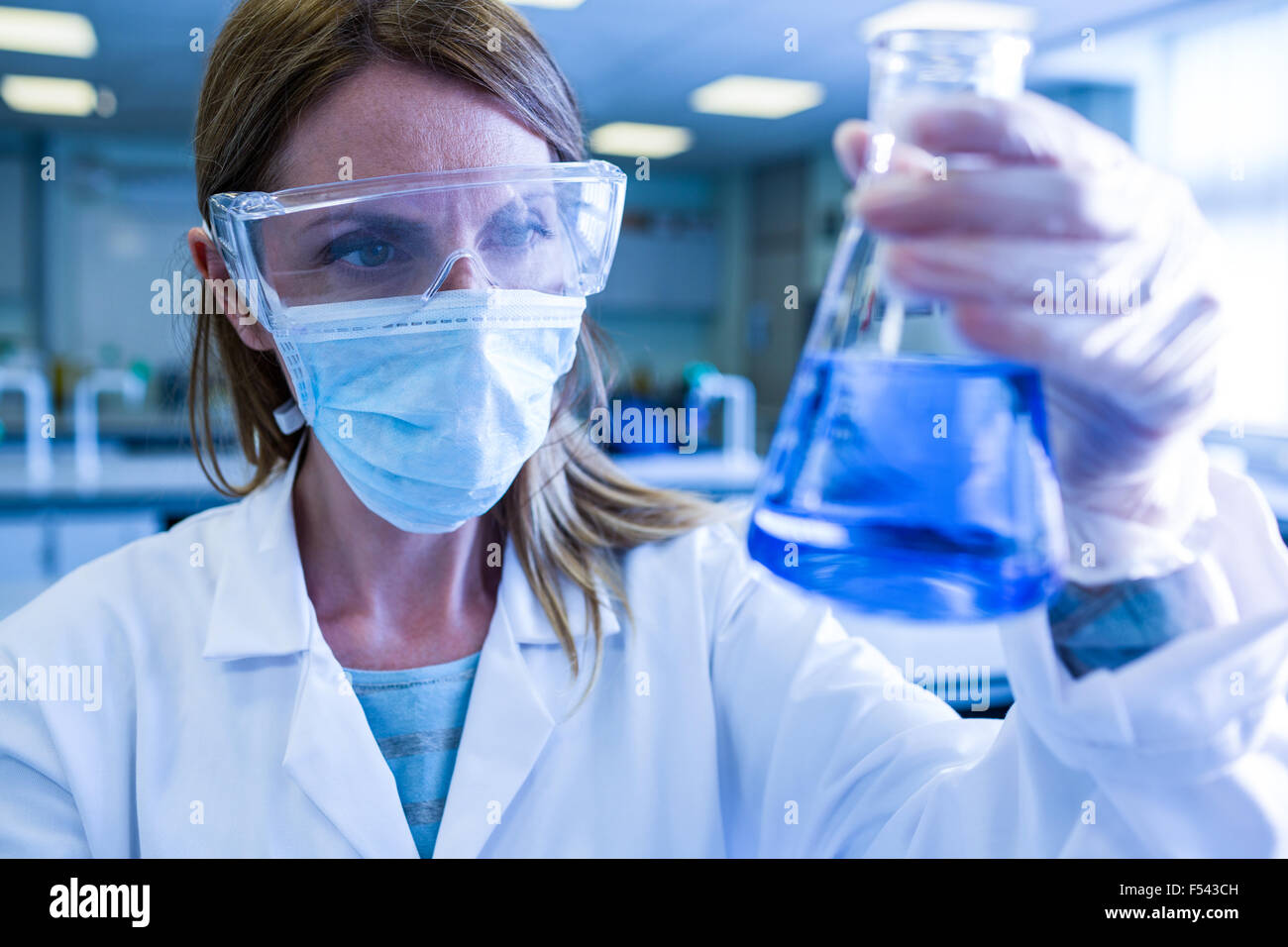 Scientist holding up beaker of chemical Stock Photo - Alamy
