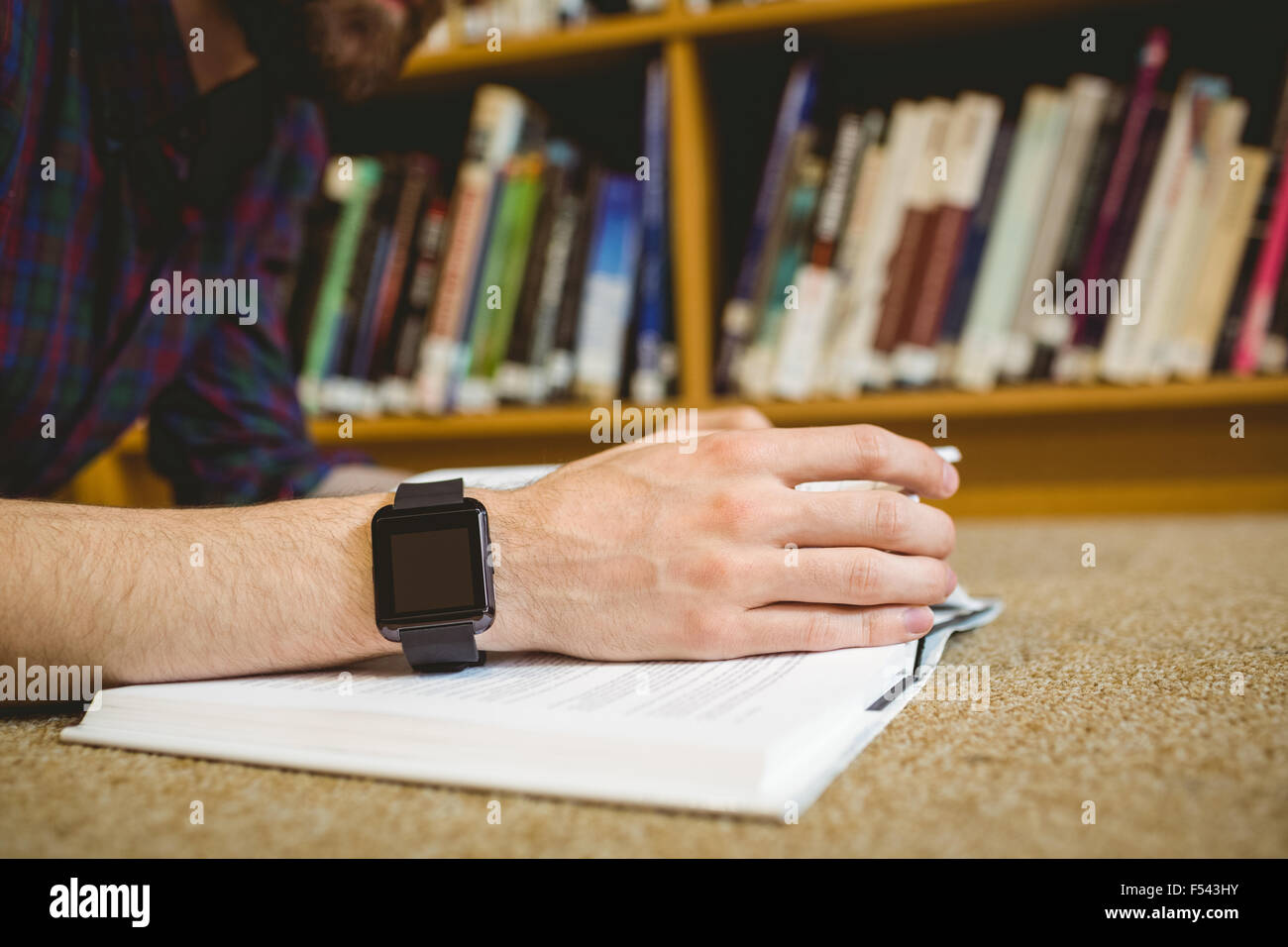 Student studying on floor in library wearing smart watch Stock Photo ...
