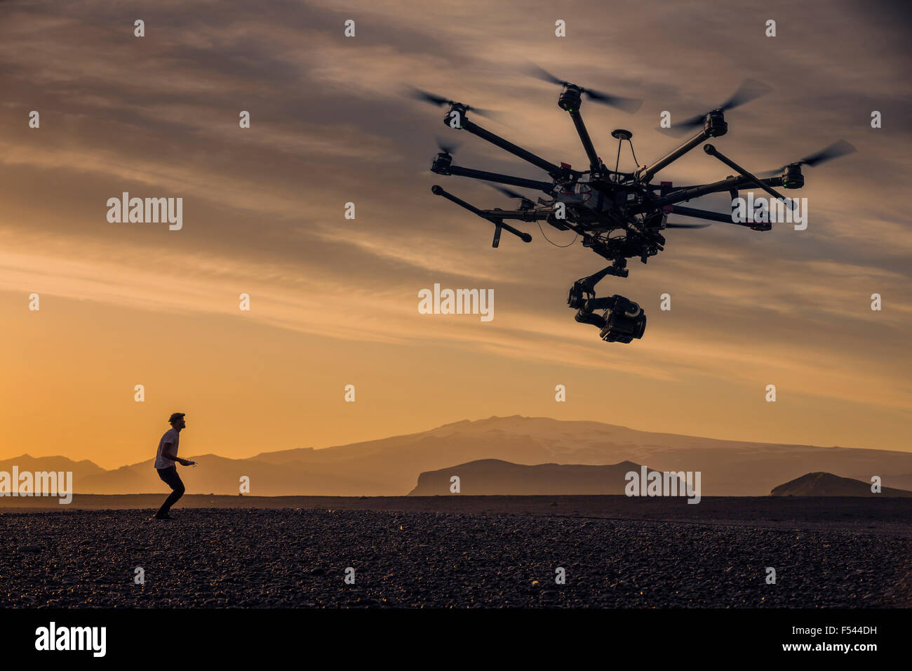Man flying a remote controlled drone with a camera at sunset in the ...