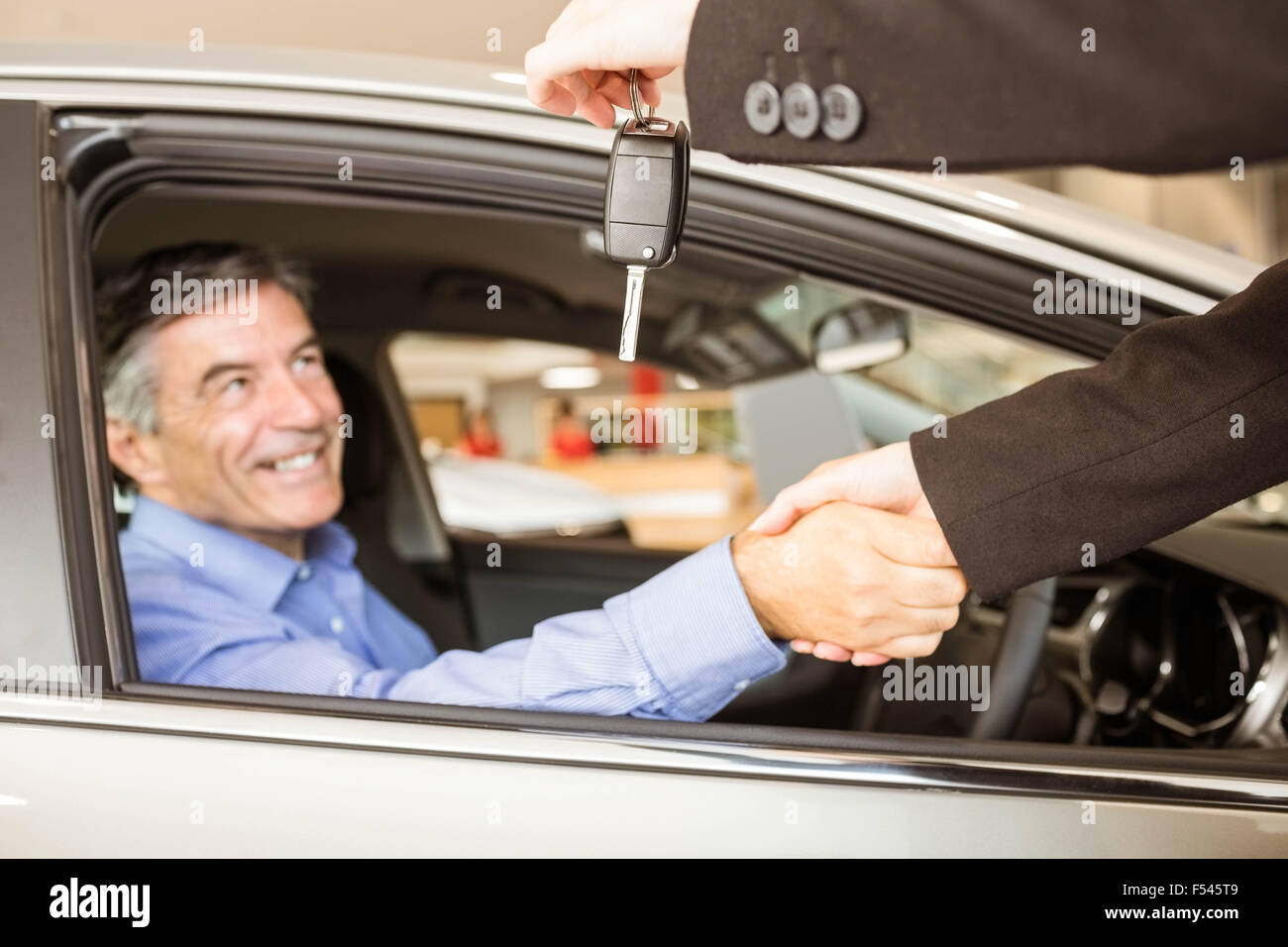 Customer receiving car keys while shaking hand Stock Photo - Alamy