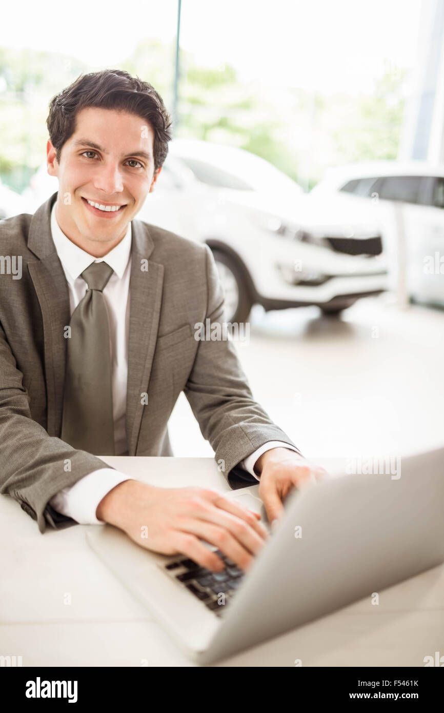 Smiling salesman typing on his laptop Stock Photo - Alamy