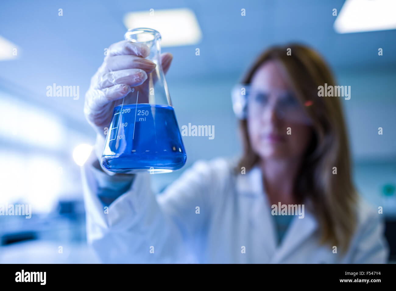 Scientist holding up beaker of chemical Stock Photo - Alamy