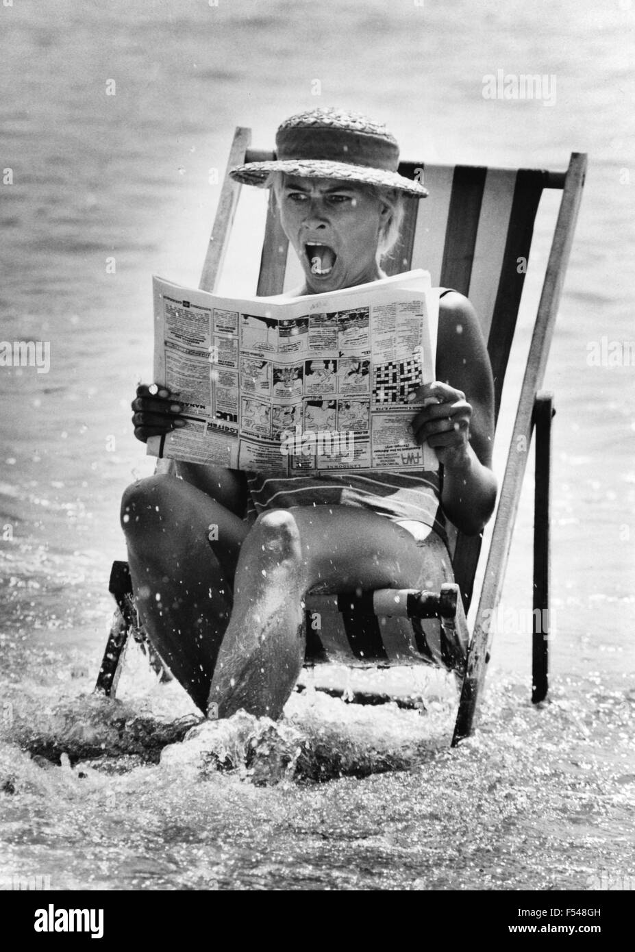 Young woman reading a broadsheet British newspaper sitting in a ...