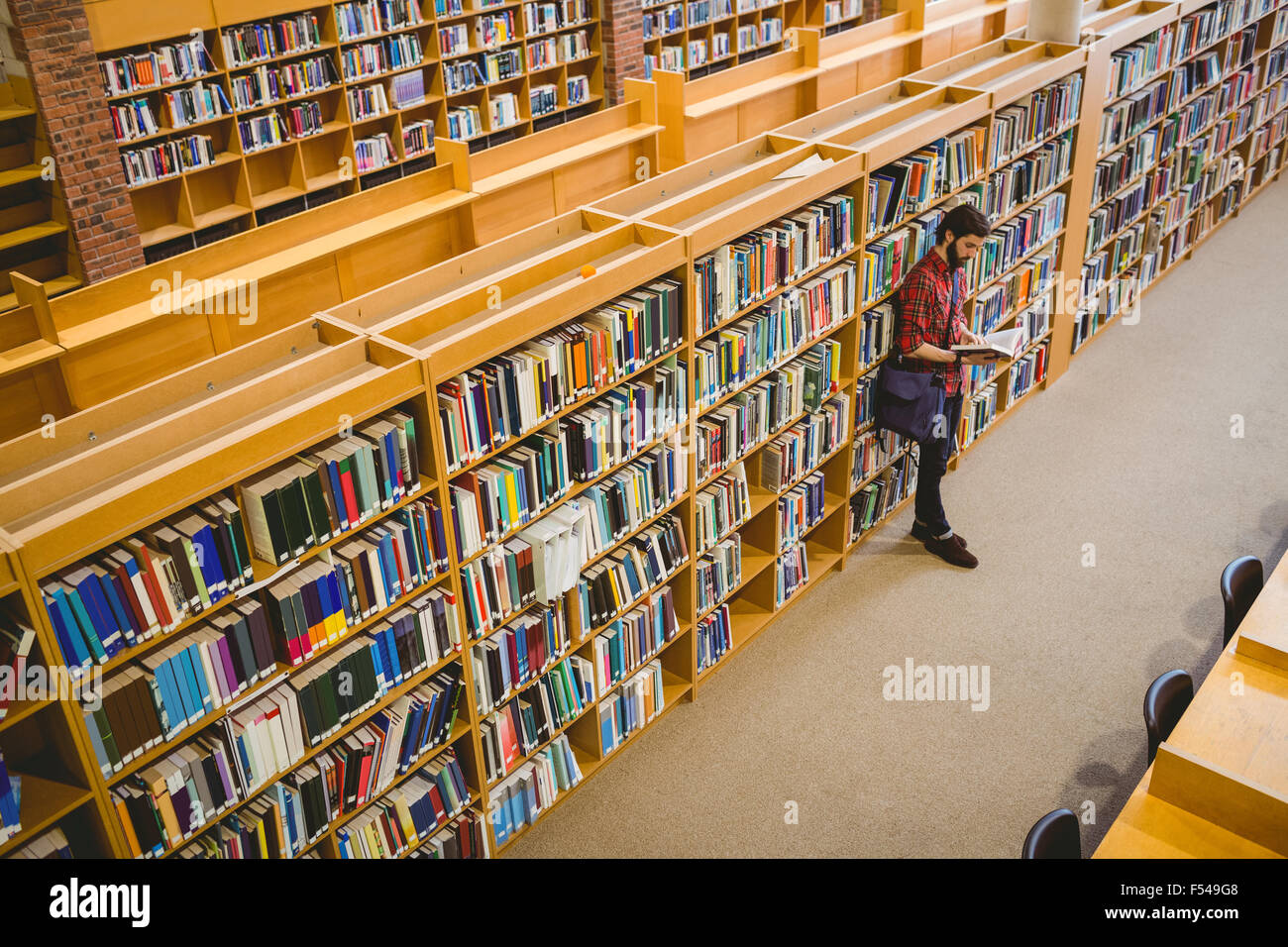 Student reading a book from shelf in library Stock Photo - Alamy