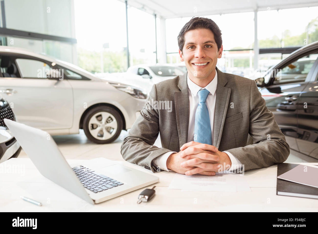 Smiling salesman behind his desk Stock Photo - Alamy