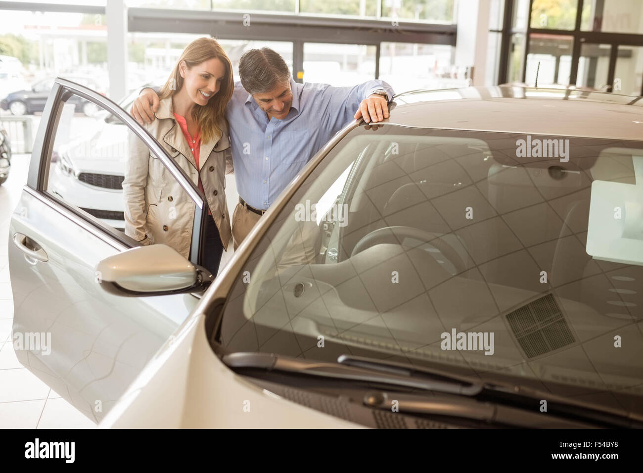 Smiling couple leaning on car Stock Photo - Alamy