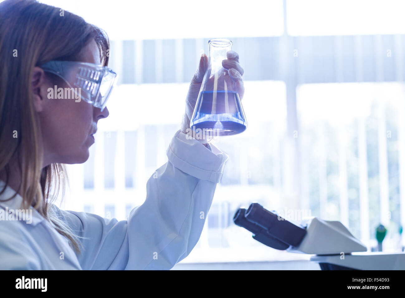 Scientist holding up beaker of chemical Stock Photo - Alamy