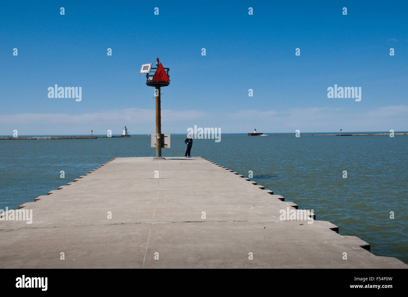 View of jetty looking out at horizon with single person at end of pier ...