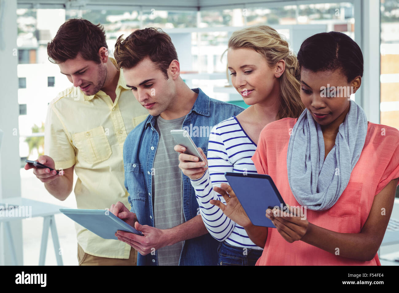 Smiling creative team standing in a line using technology Stock Photo ...