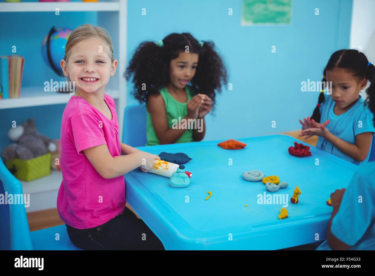 Smiling girls playing with modelling clay Stock Photo - Alamy