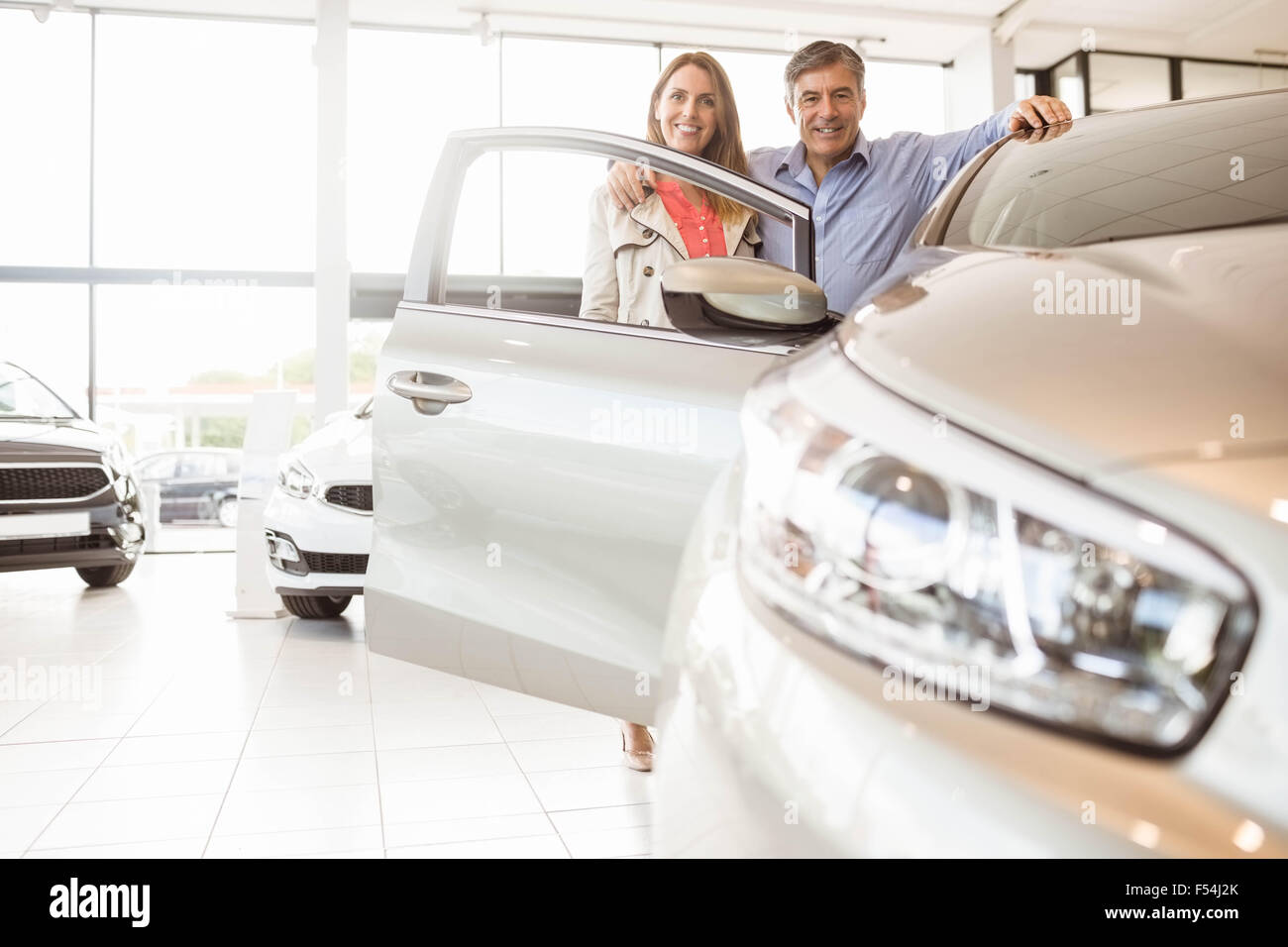 Smiling couple leaning on car Stock Photo - Alamy