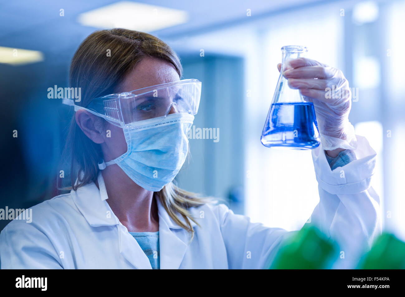 Scientist holding up beaker of chemical Stock Photo - Alamy