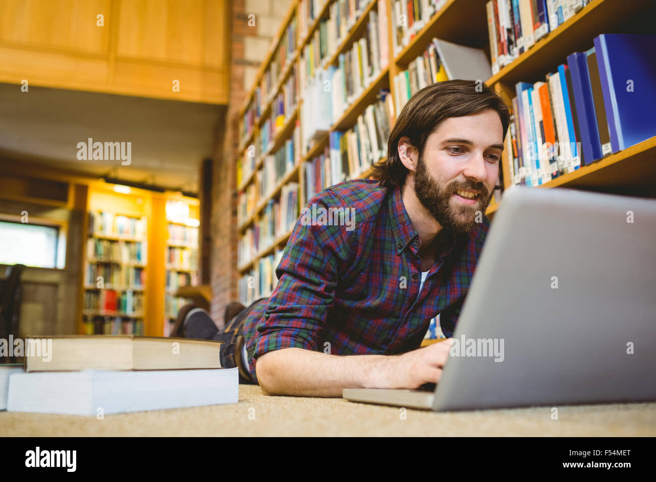 Student using laptop on floor in the library Stock Photo - Alamy