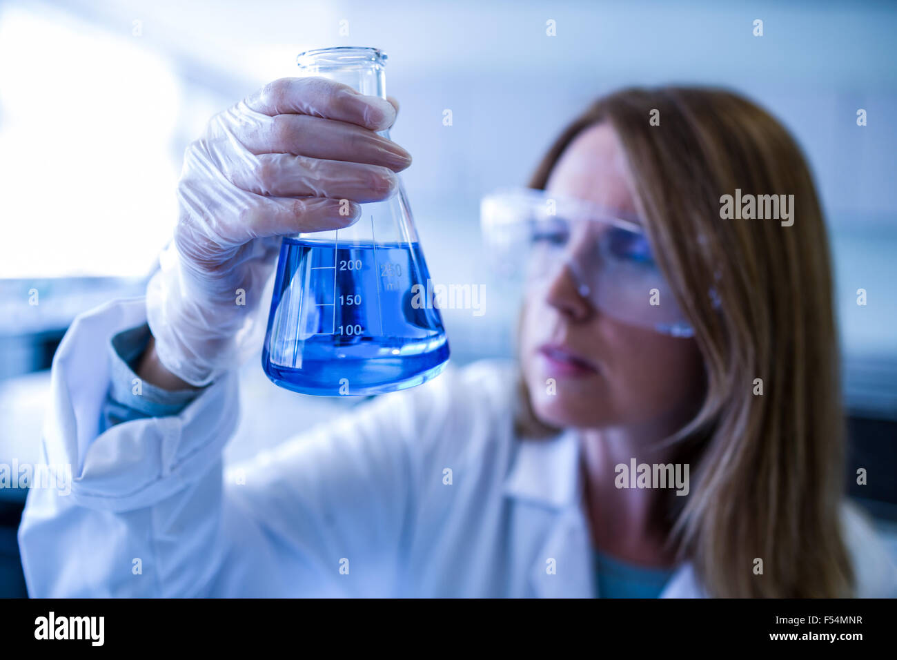 Scientist holding up beaker of chemical Stock Photo - Alamy