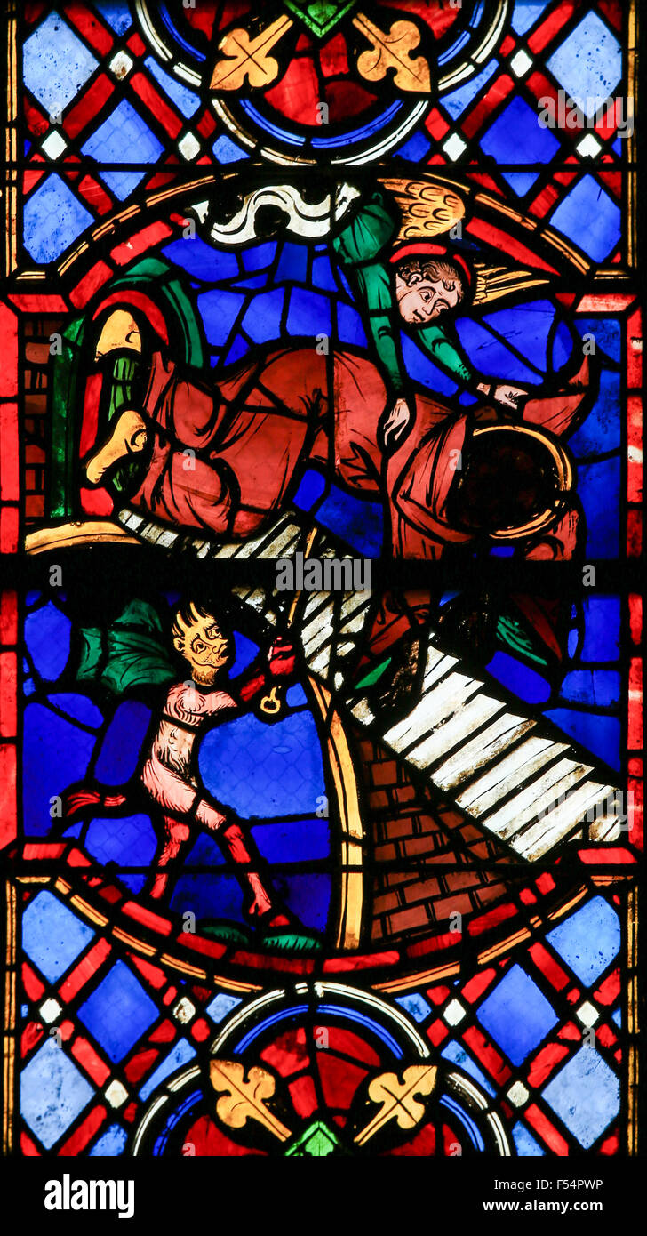 Stained glass window depicting a Devil and an Angel fighting for the ...