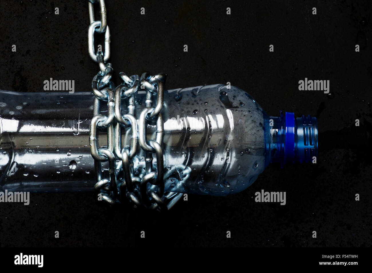 Plastic bottle with water remains wrapped steel chain on black ...