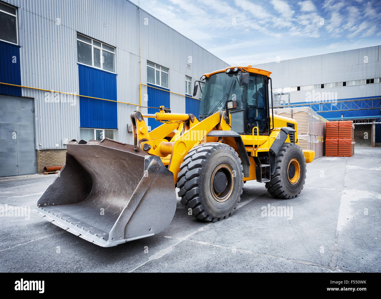 Yellow tractor with bucket standing in the yard of warehouse Stock ...