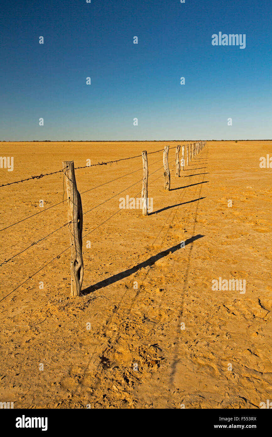 Posts & wire fence crossing vast barren treeless Australian outback red ...