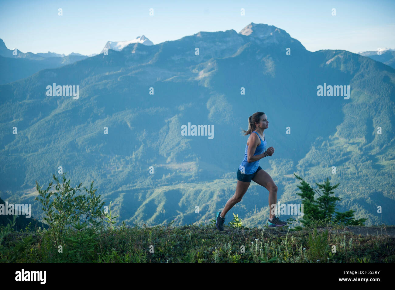 Side view of sporty woman jogging on mountain path Stock Photo - Alamy