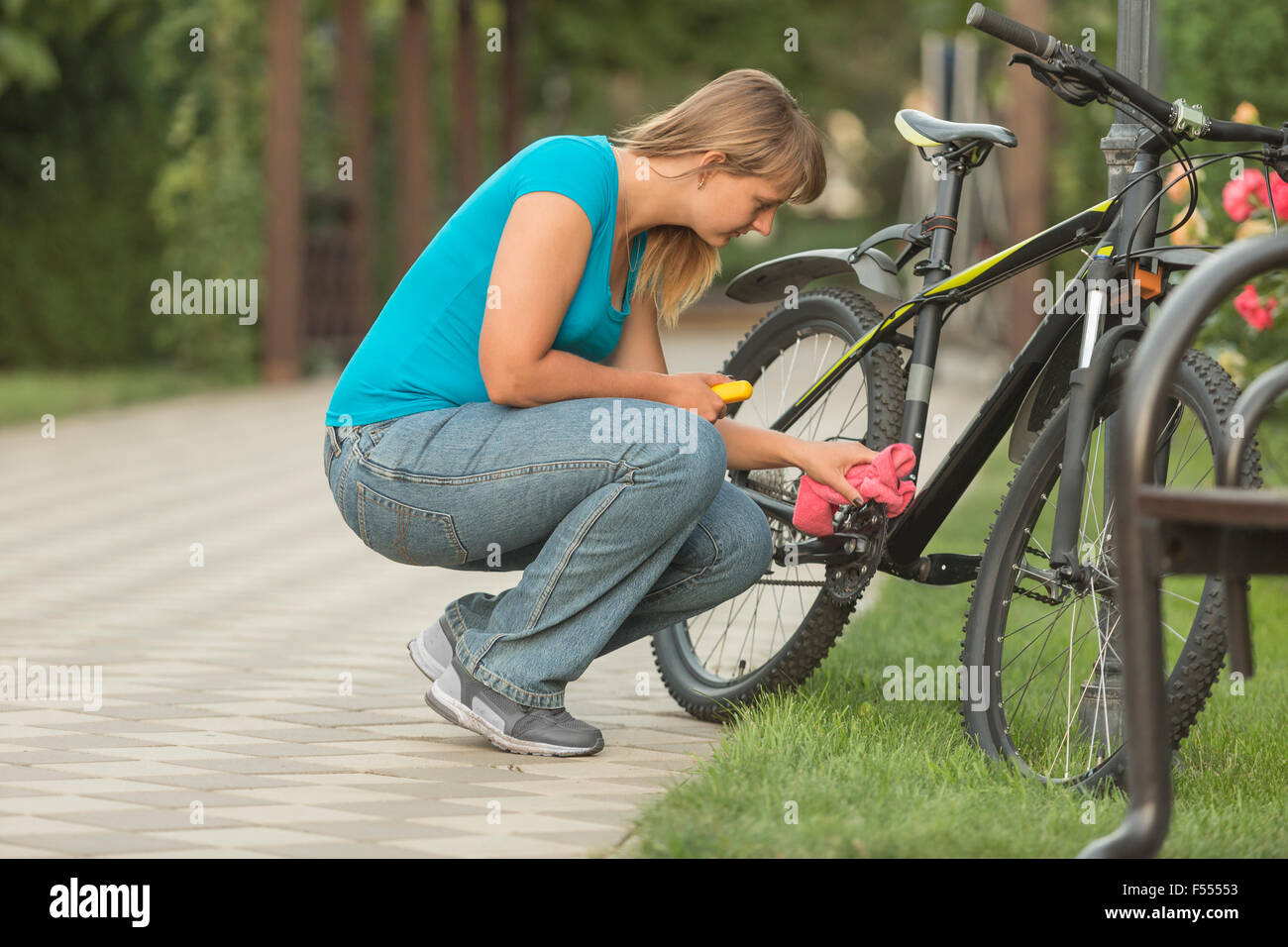 Side view of woman repairing bicycle in park Stock Photo - Alamy