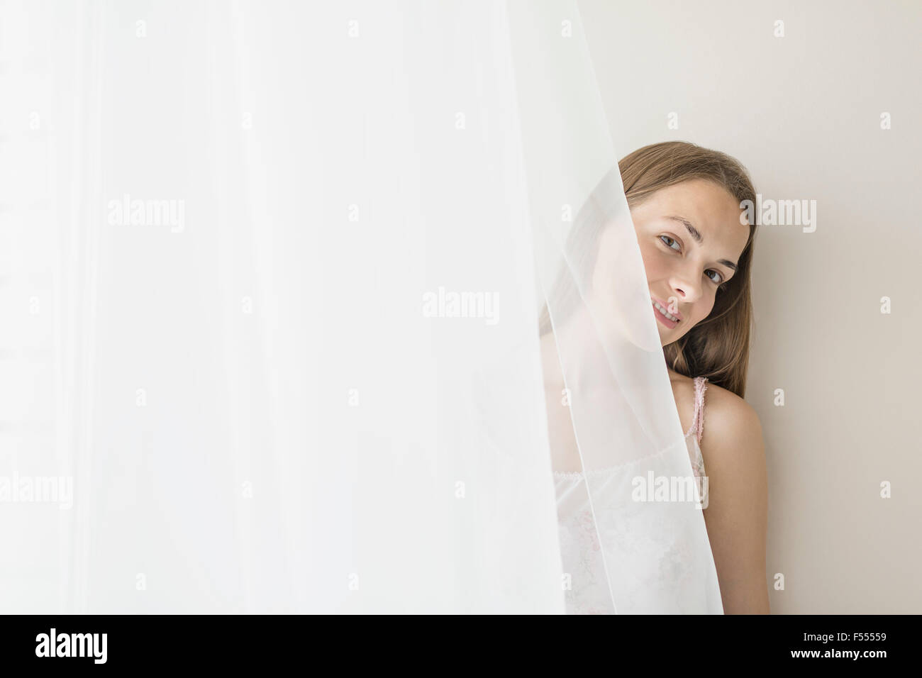 Woman hiding behind curtain hi-res stock photography and images - Alamy