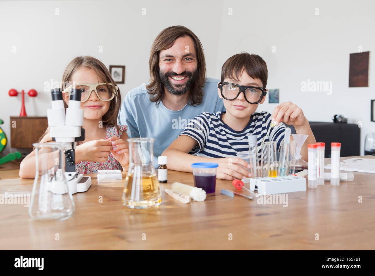 Portrait of father and children doing science experiment at home Stock ...
