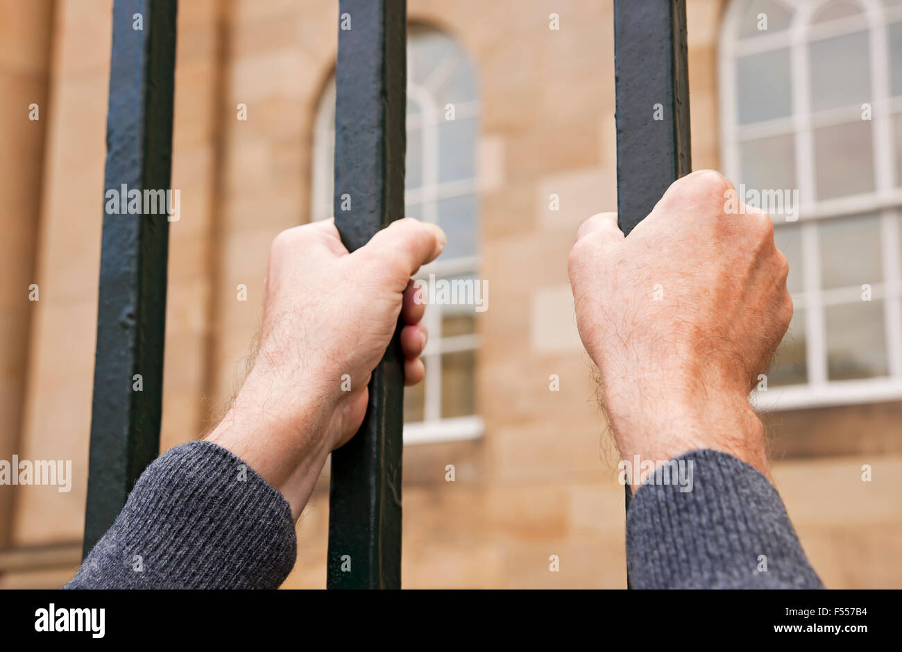 Close up of man prisoner holding metal iron bars of window in prison ...