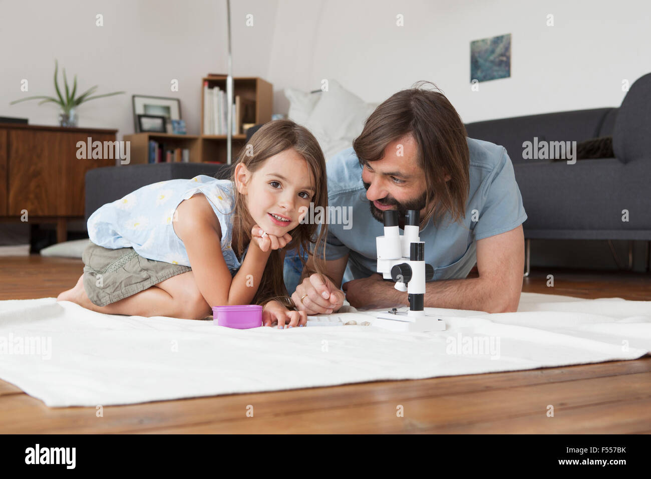 Father and daughter using microscope on carpet at home Stock Photo - Alamy