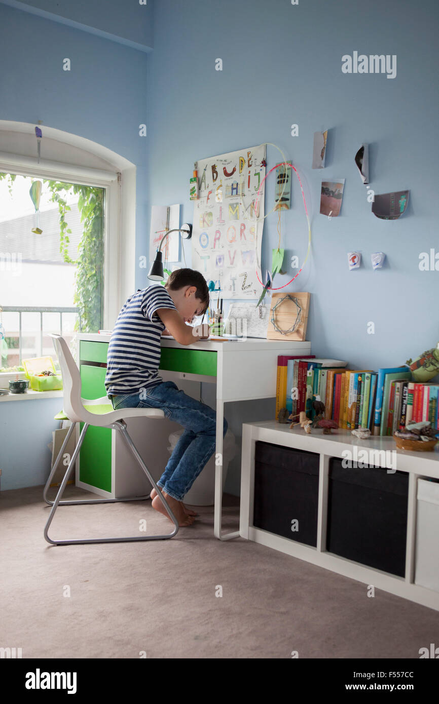 Side view of boy doing homework at table in house Stock Photo - Alamy