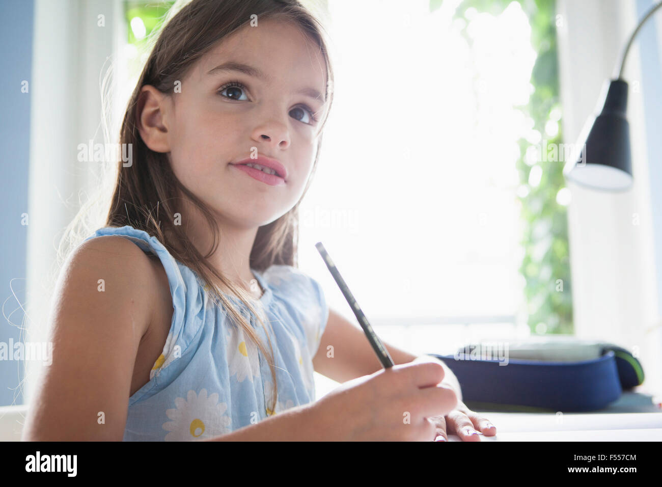 Cute girl doing homework at table Stock Photo - Alamy
