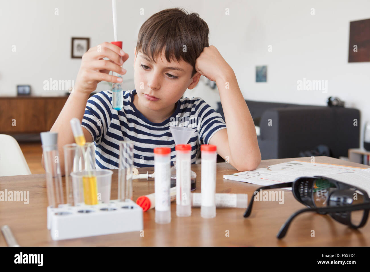 Boy looking at test tube while doing science experiment at home Stock ...