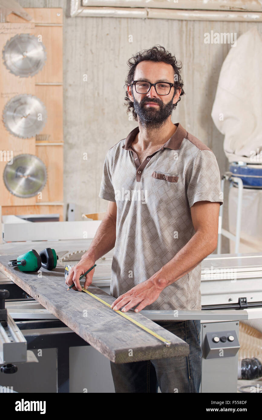 Portrait of male carpenter measuring wood in workshop Stock Photo - Alamy