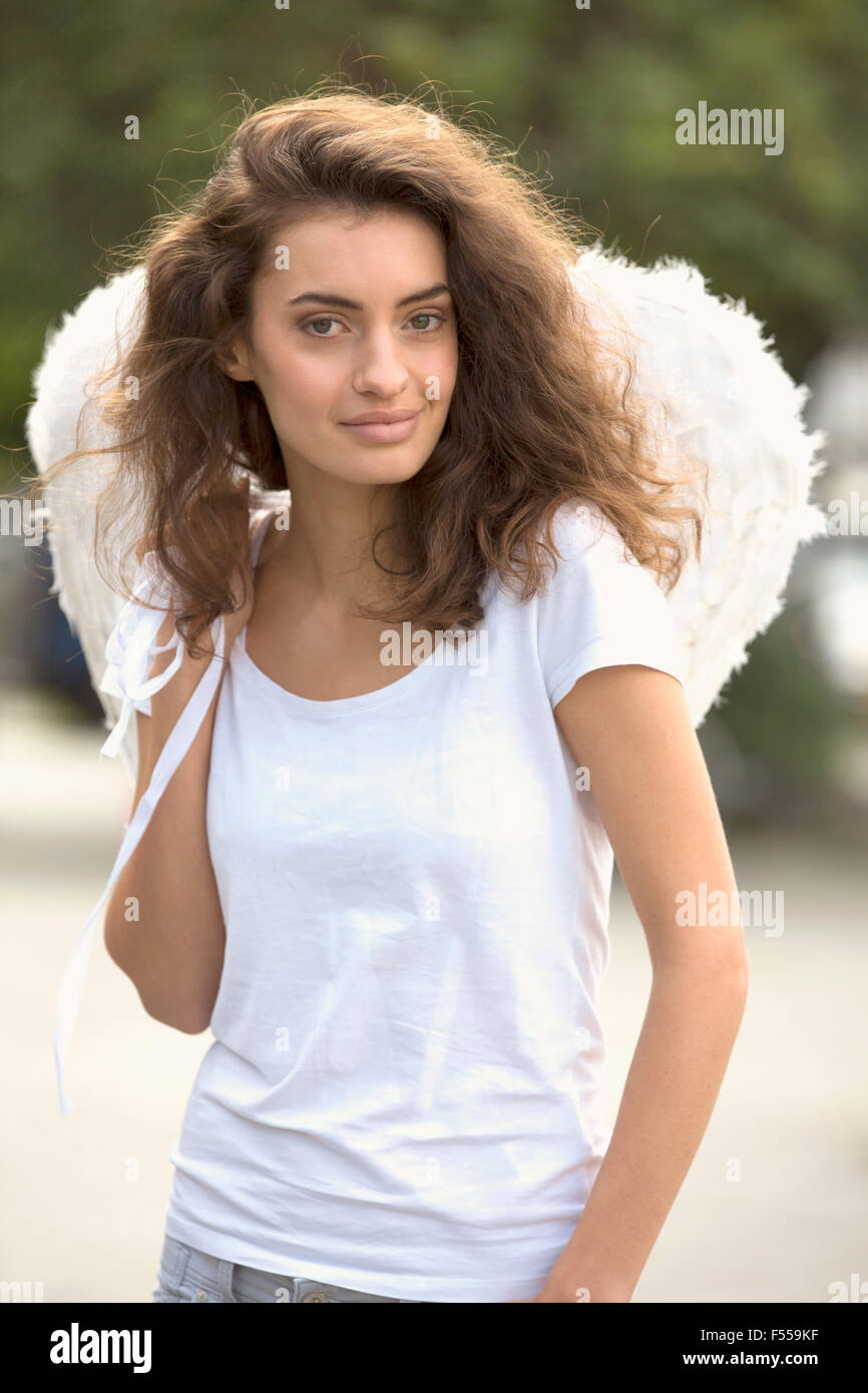 Portrait of smiling woman wearing angel wings outdoors Stock Photo - Alamy