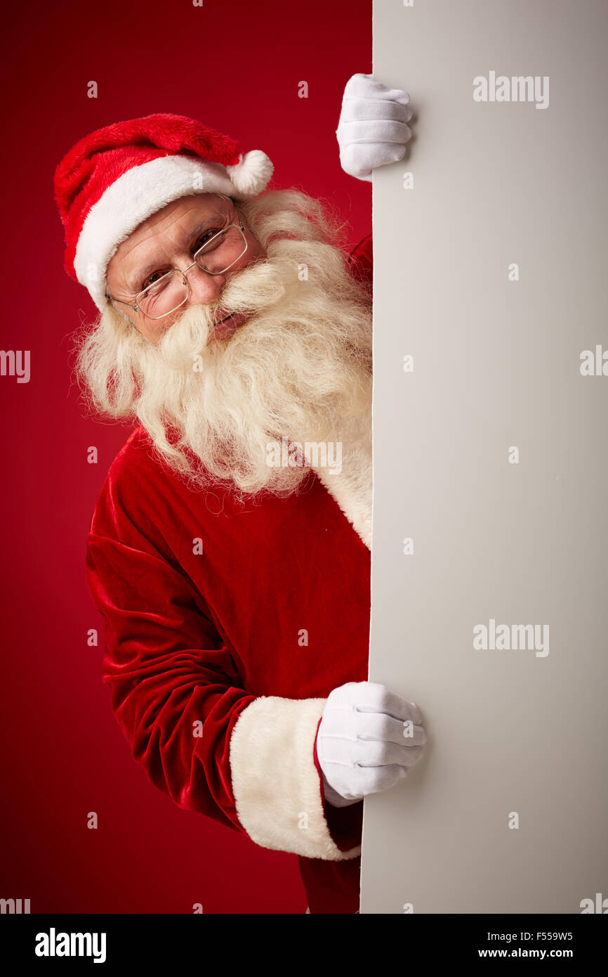Happy Santa looking at camera out of blank billboard Stock Photo - Alamy