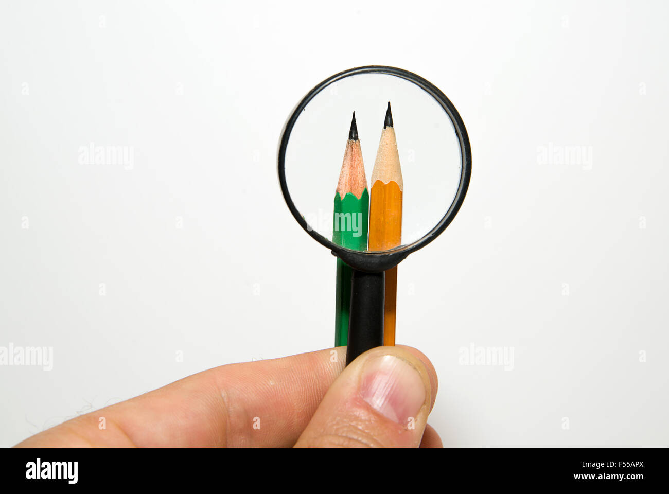 The hand with a magnifying glass and two pencils on over white Stock ...