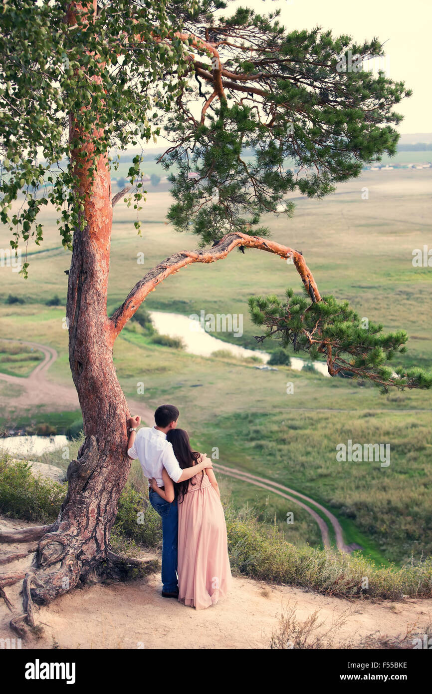 happy couple standing under a beautiful tree and looking into the ...